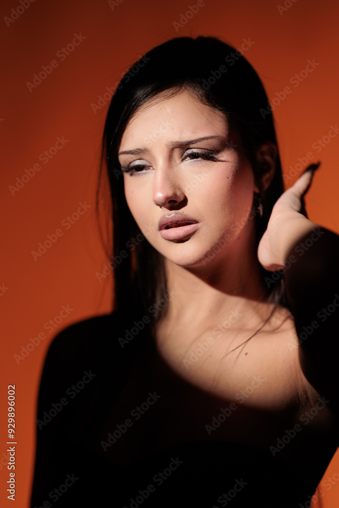 Brunette girl posing in a beam of light in the studio, on a red ...
