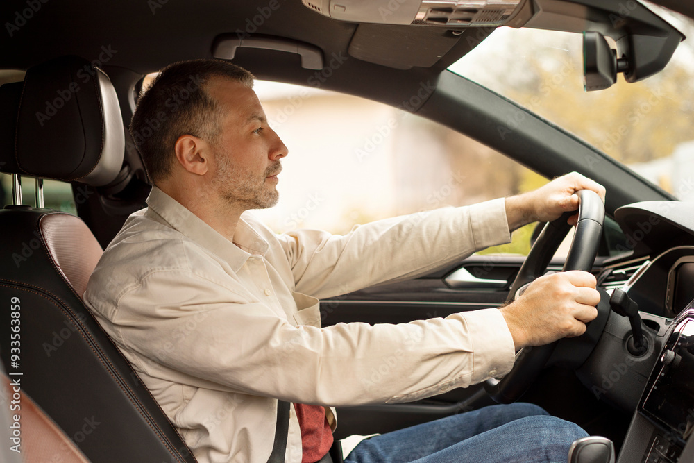 Side view of confident middle aged man in casual driving new car ...