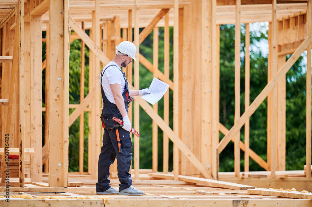 Engineer constructing wooden two-story frame house. Bearded man in ...