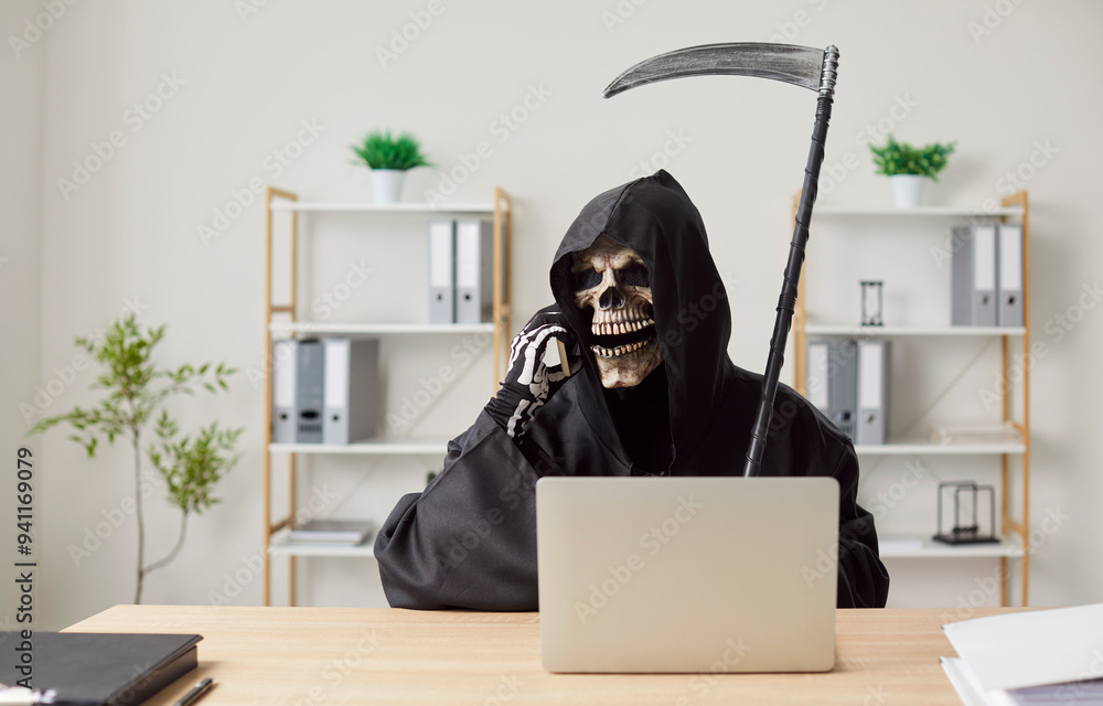 Devil employee in black cloak and skeleton mask sitting at workplace in ...