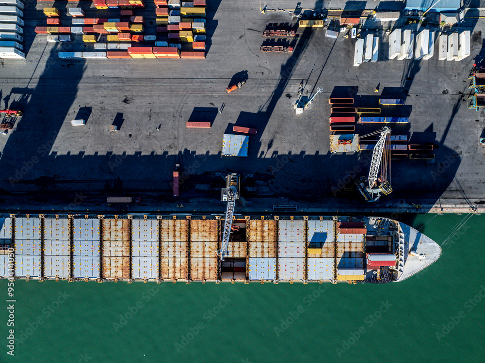 Container ship loaded at dockside. Cranes operating to lift containers ...