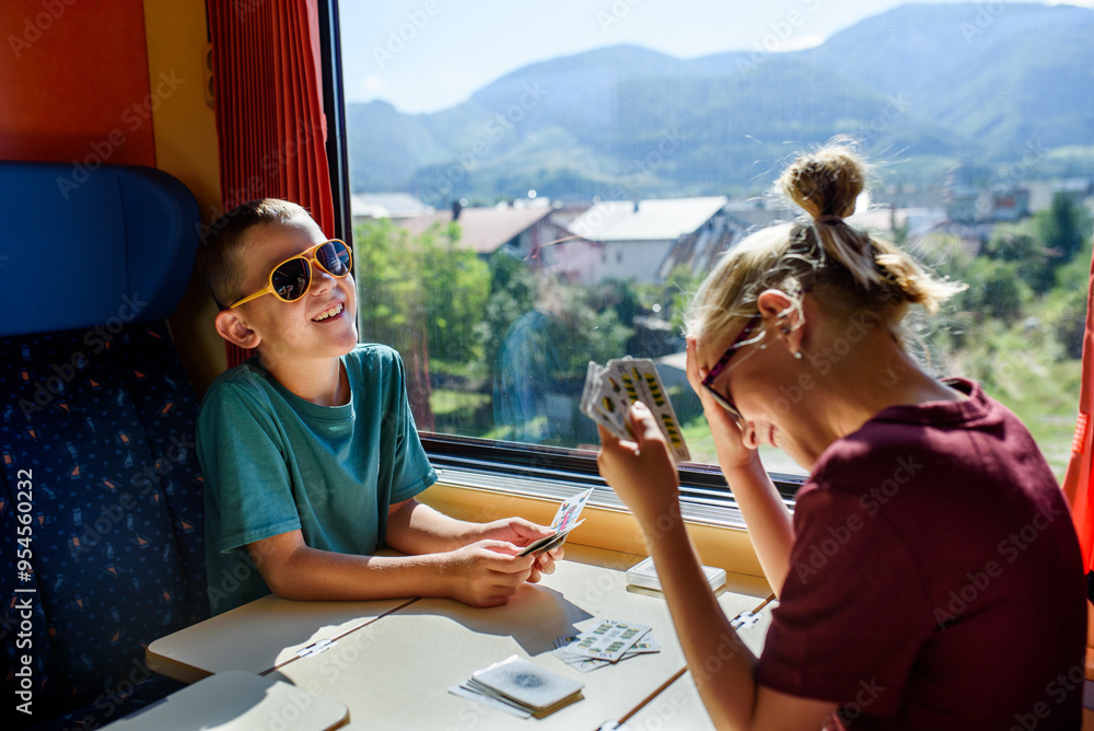Siblings sitting in train, playing cards, having fun. Family going on ...