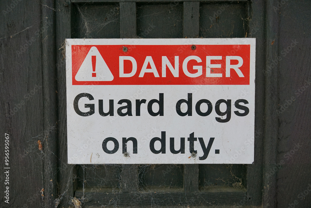 Guard dogs on duty warning sign on boundary fence. Danger notice of ...