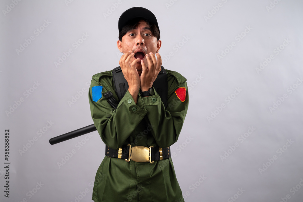 Asian male security officer in a green uniform and black cap, holding a ...