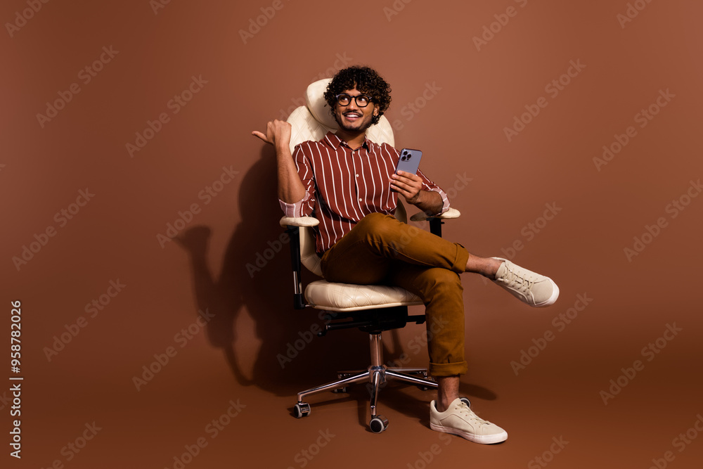 Full size photo of nice young man sit chair direct finger empty space ...