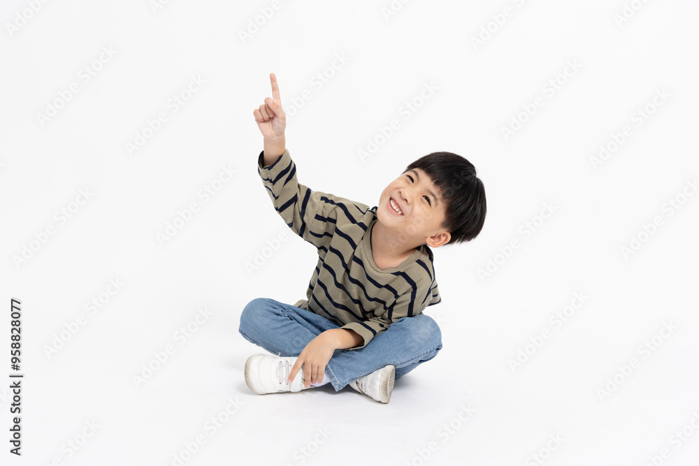 Happy Asian little boy pointing up with empty copy space and sitting on ...