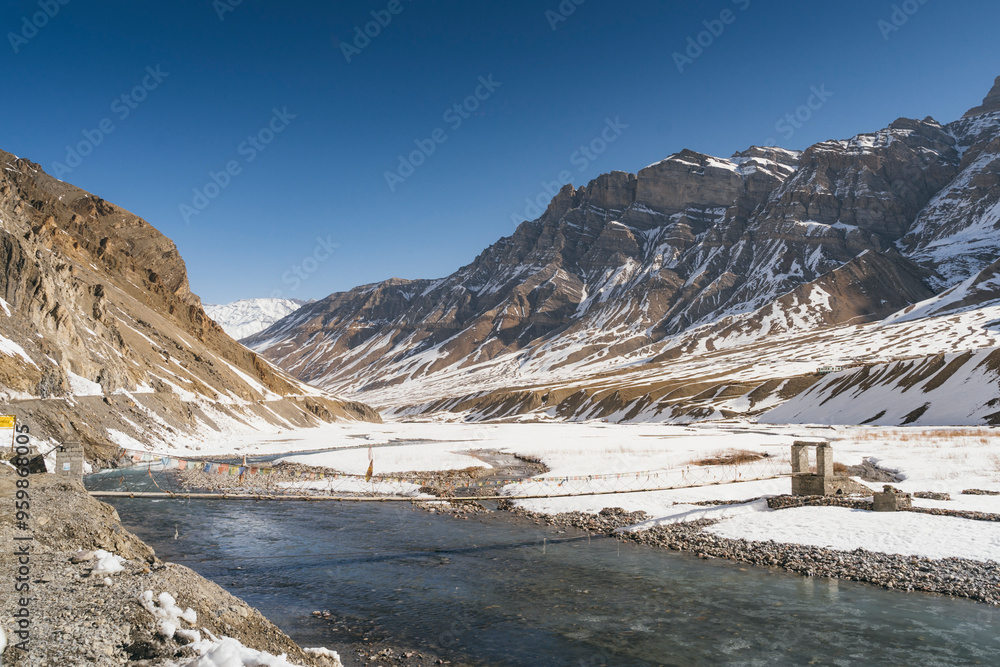 View of snow mountains and a river with rocks and a village in the ...