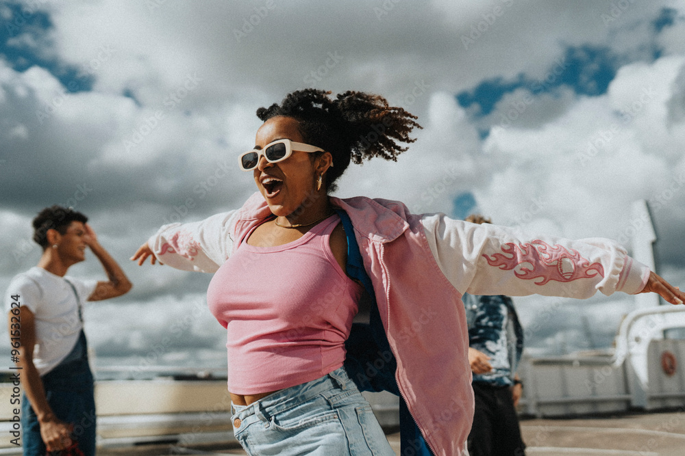 Carefree curly hair woman in pink letterman jacket with arms ...