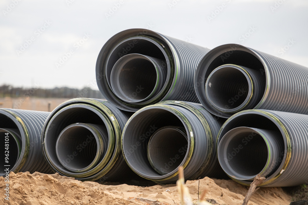 A stack of grey ribbed or corrugated industrial heavy PVC underground ...