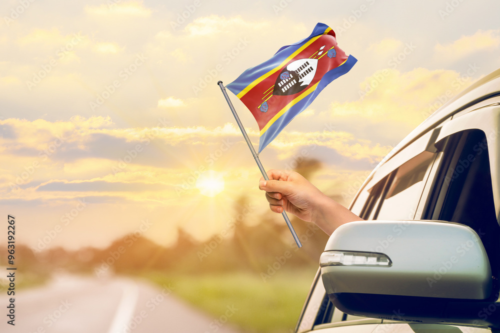 Waving the Eswatini flag against the sunrise or sunset from a car ...