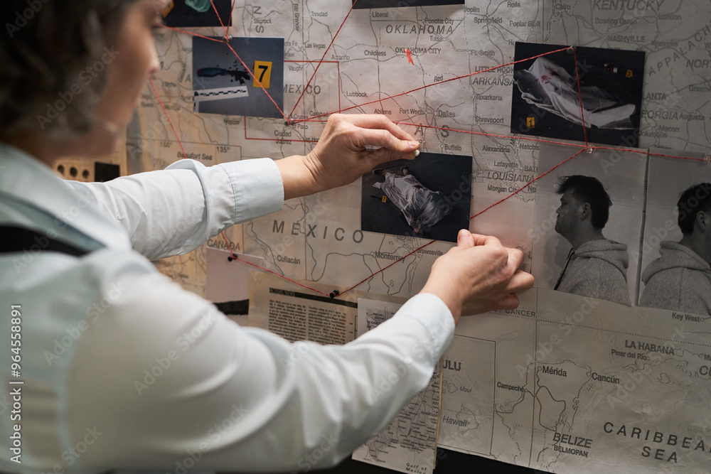 Investigative professional analyzing a detailed board with photographs ...