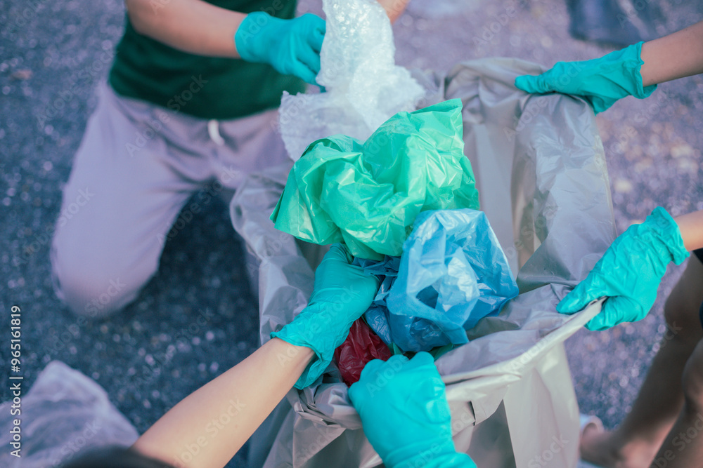 Two women and a girl are working together, collecting trash that has ...