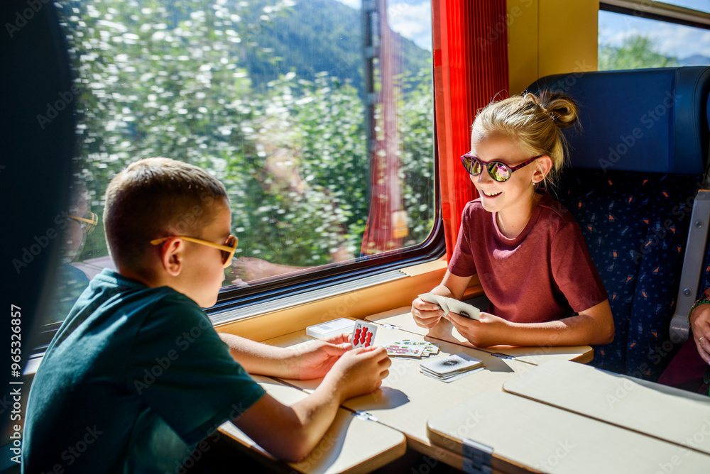 Siblings sitting in train, playing cards, having fun. Family going on ...