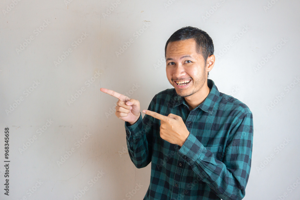 Young Adult Asian men pointing finger to the left with smiling face and ...