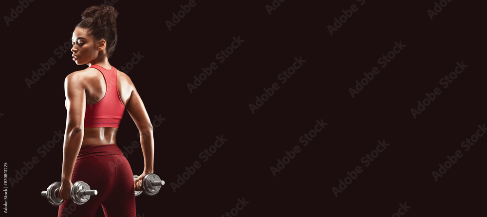 Back view of african female bodybuilder with barbells over black studio ...