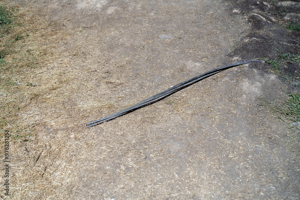 isolated wire sprawls across a trodden path, symbolizing disruption and ...