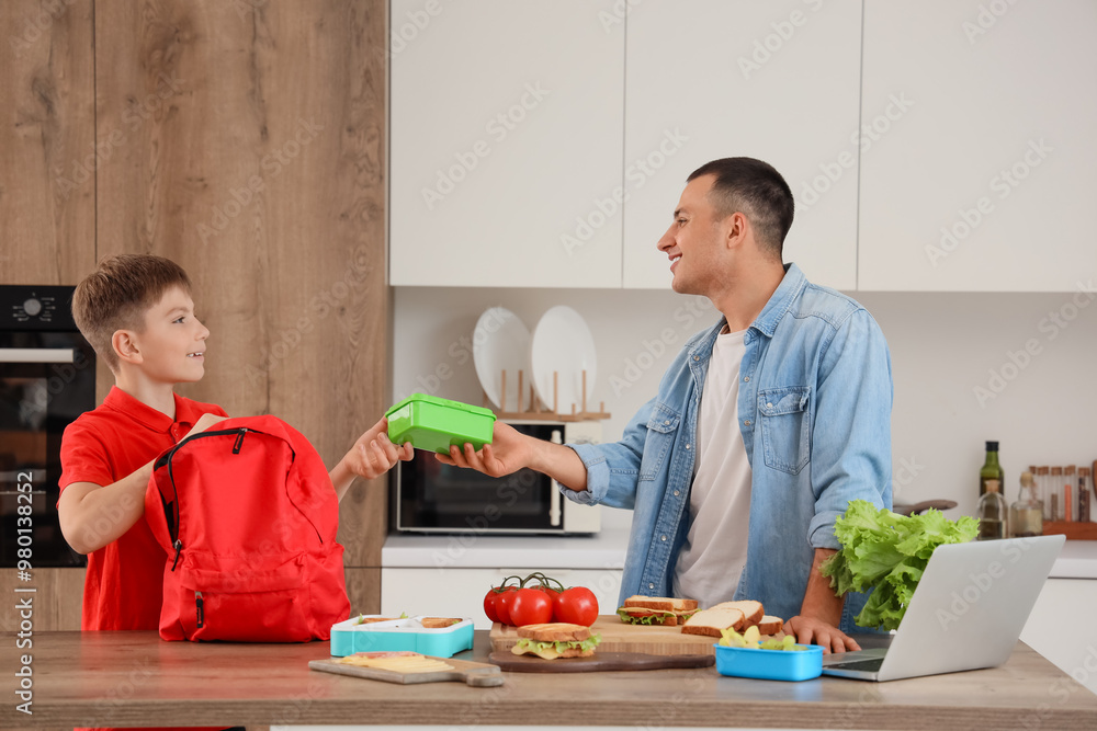 Little boy with his father packing school lunchbox into backpack in ...