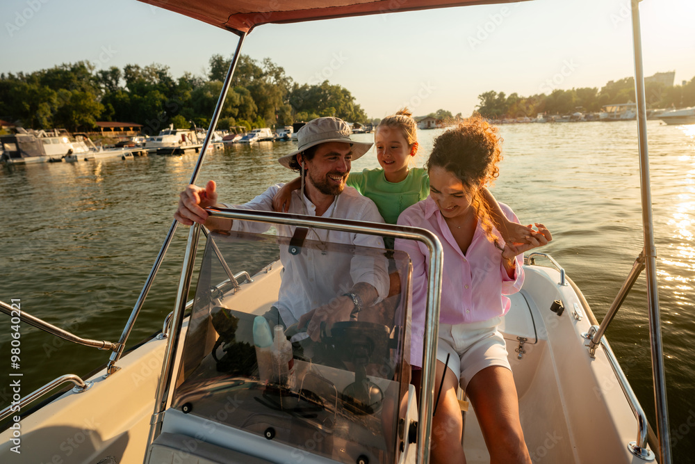 Family enjoying a boat ride on a sunset, father steering the boat, the ...