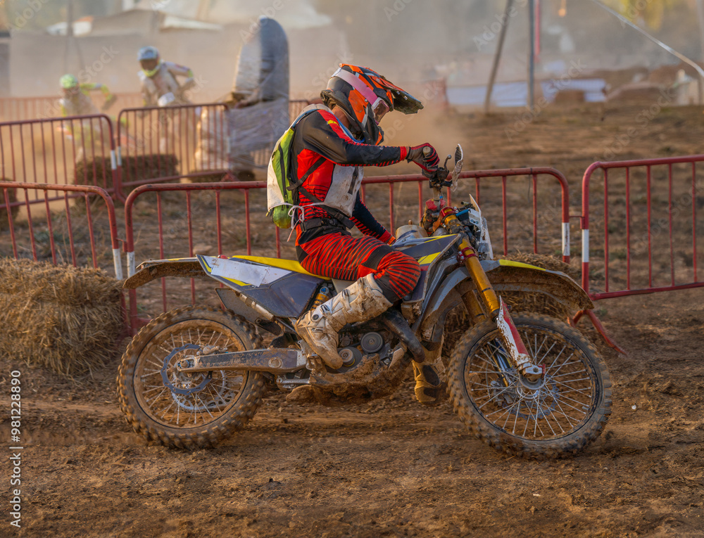 Side view of a motocross rider in action taking a turn on a dirt track ...