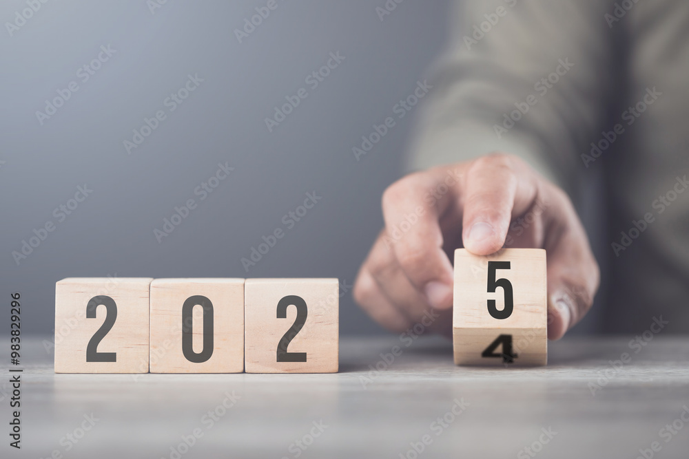Hand replaces "2024" with "2025" using number blocks, symbolizing the ...