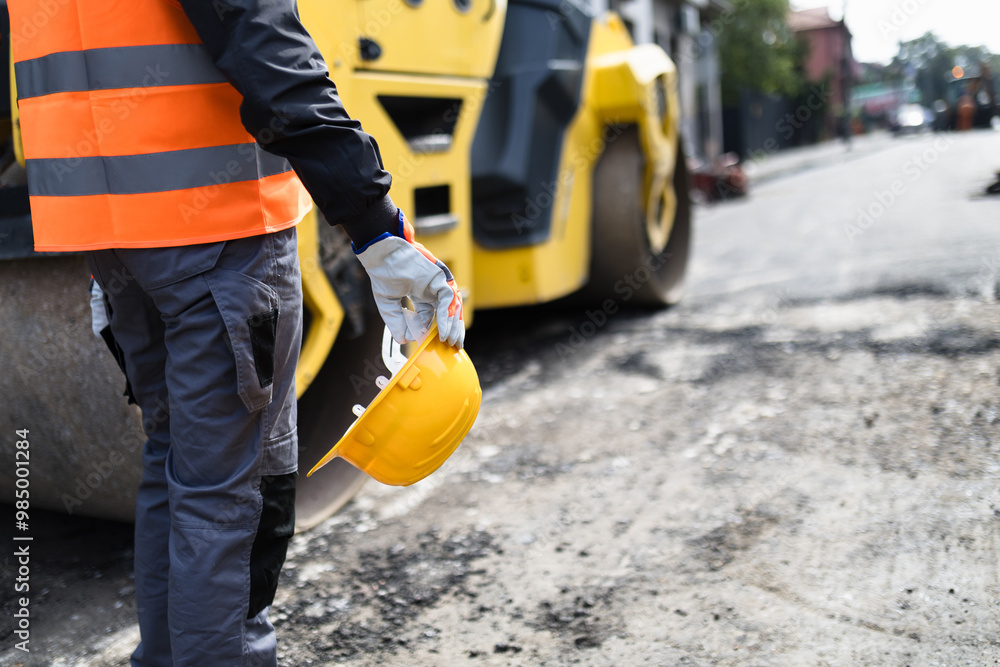 Construction worker holding a safety helmet while supervising roadworks ...