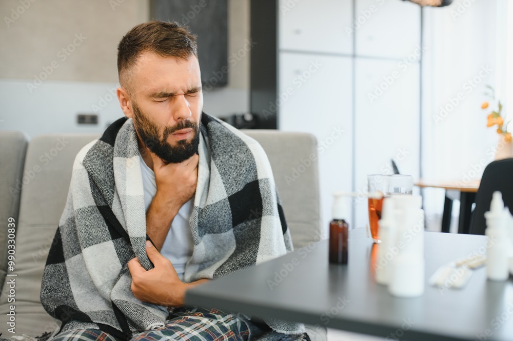 Sick man holding his chest in pain while coughing in the living room ...