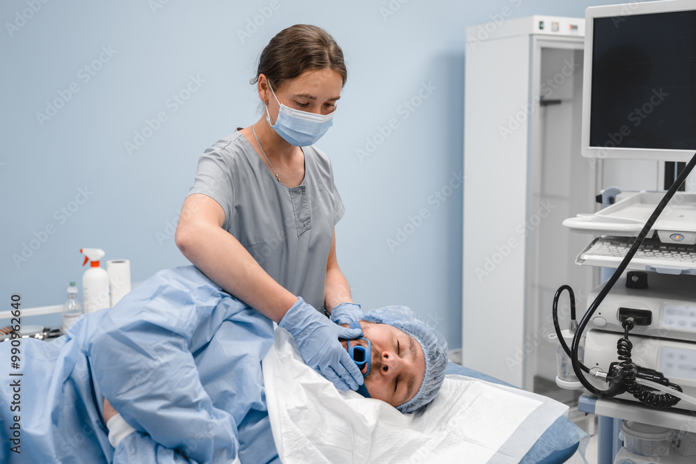 Male patient man laying at the bed while assistant holding special equipment at his mouth ...