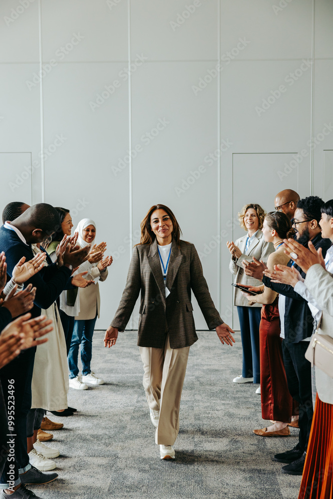 Successful female leader walking between supportive colleagues clapping ...