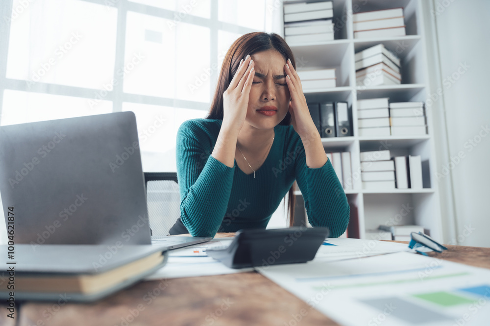 Overwhelmed by Stress: A woman sits at her desk, hands on her head ...