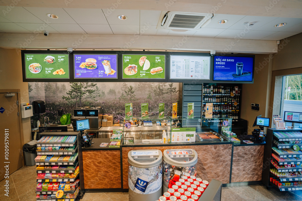 A fast-food counter in a convenience store with digital menu boards ...