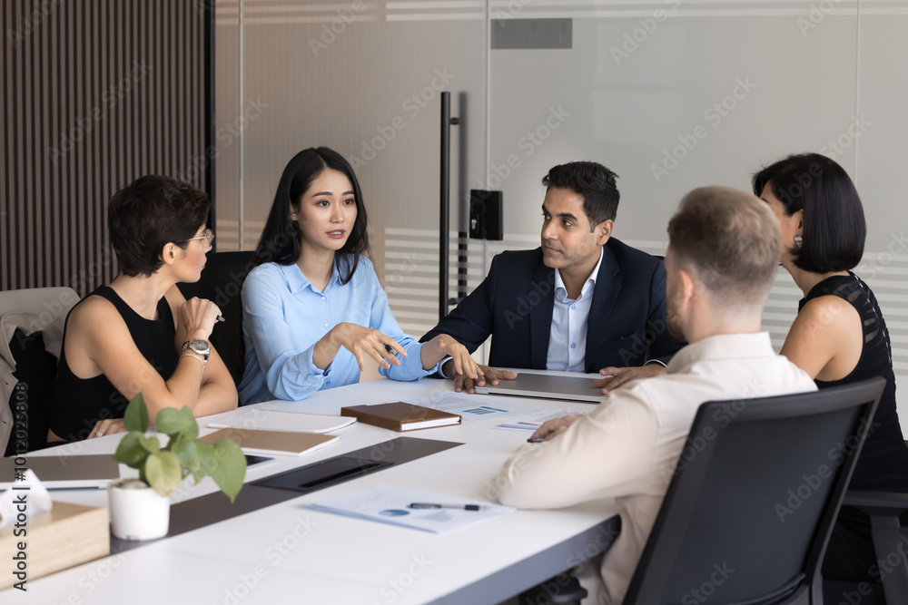 Serious young Asian employee girl speaking at team meeting, offering ...