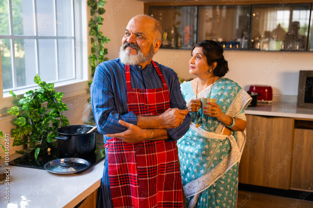 Charming Indian couple having tea in a modern kitchen, relaxing while ...