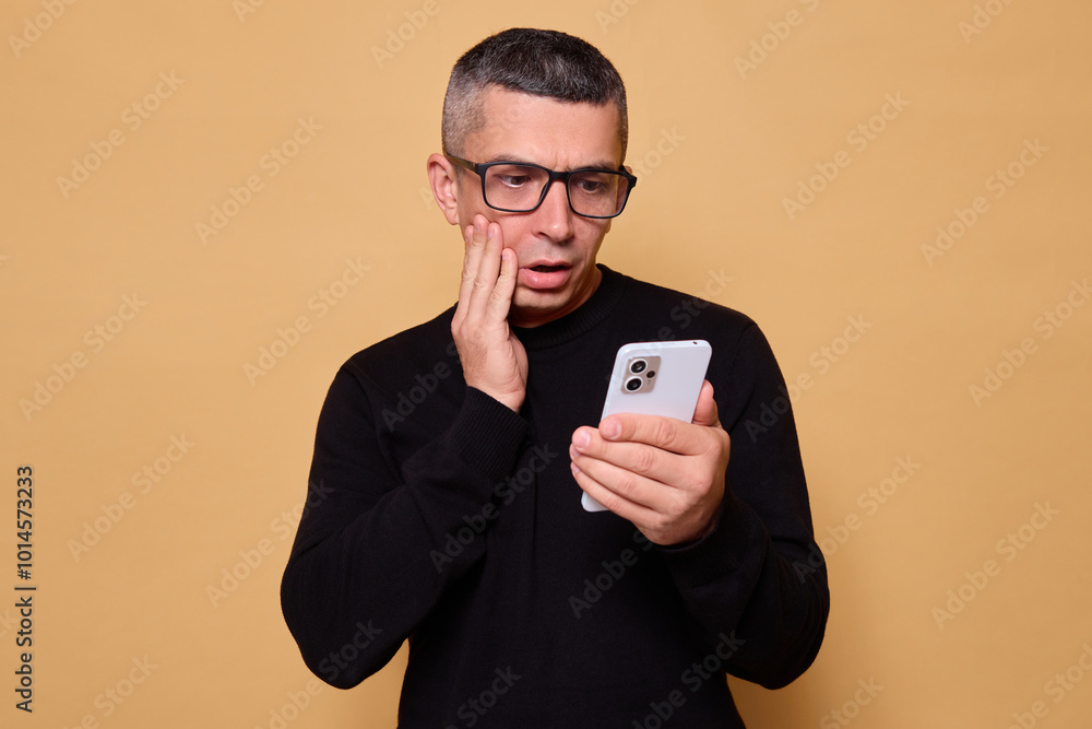Shocked guy wearing glasses and jumper staring at smartphone feeling ...