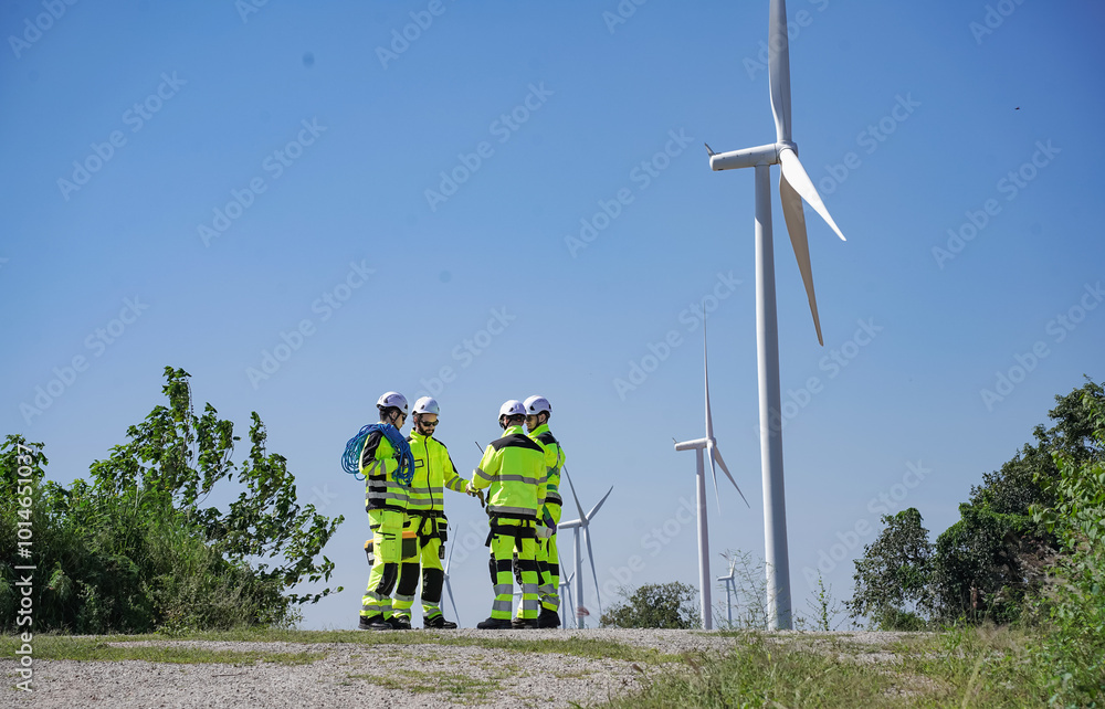 Maintenance engineer team standing at windmills at wind turbine farm ...