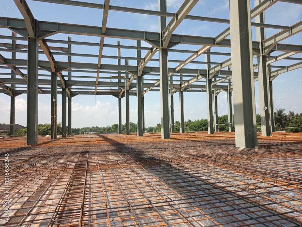 The photo shows a construction site with a steel frame structure. The ...