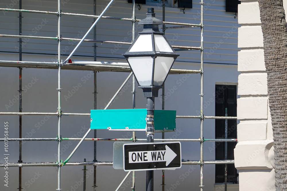 Green Street signs on a light pole with construction site scaffolding ...