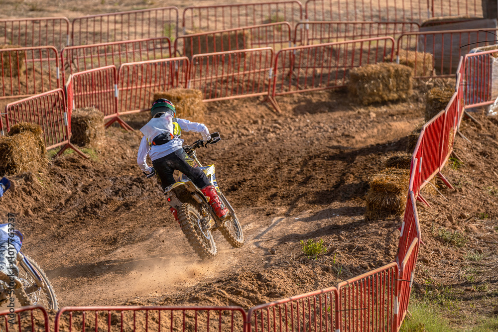 Motocross riders cornering standing up on their bikes racing on a muddy ...