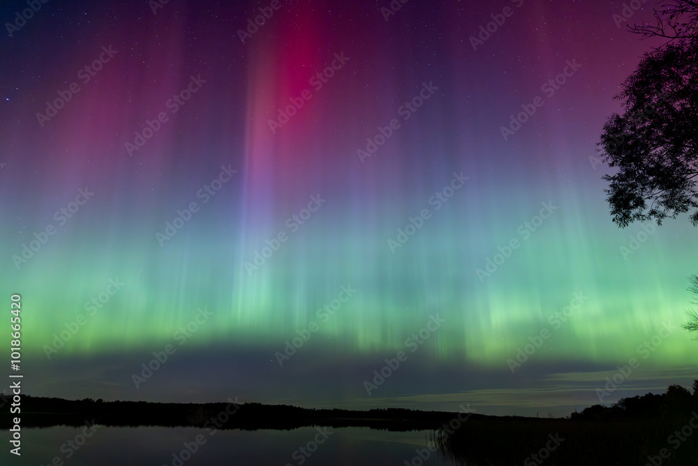 Northern Lights erupt over a Minnesota lake in the dark sky overhead ...