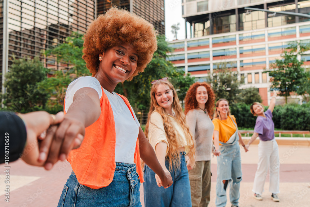 Diverse group of girls holding hands outdoors, smiling and enjoying ...