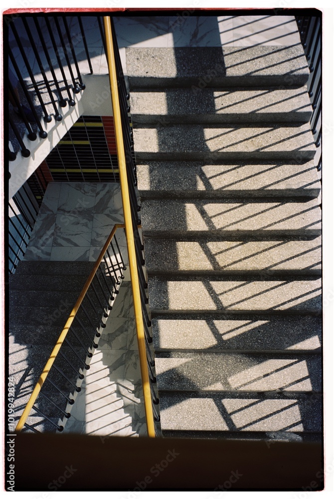 Spiral staircase with shadows and yellow railing in a modern building ...