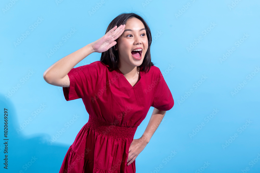 Asian woman wearing a red dress poses with her hand raised in a playful ...