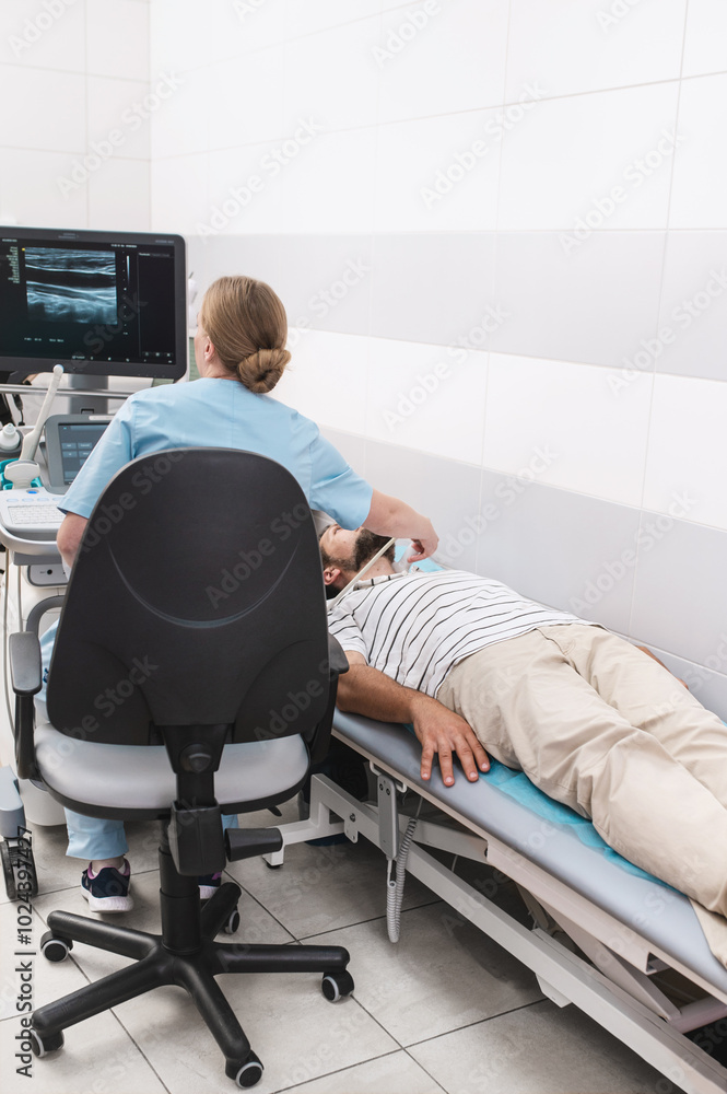 Female doctor performs ultrasound examination of men's thyroid in ...