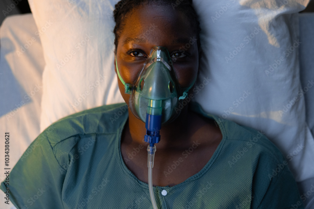 In the hospital room, a young patient manages asthma symptoms, wearing ...