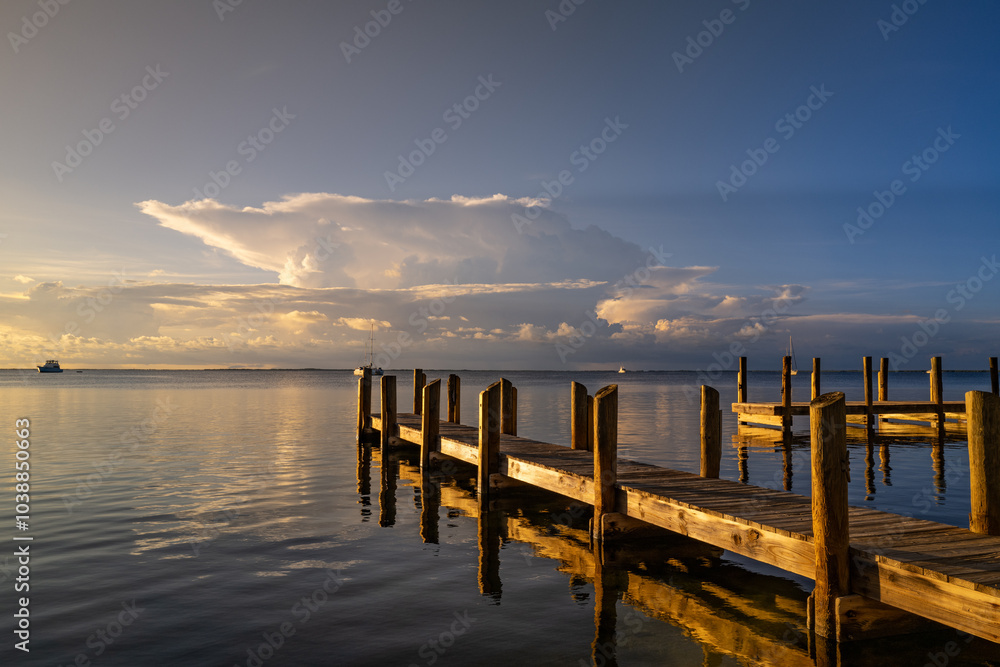 Sunset begins to fall over a wooden boat dock in the Gulf of Mexico on ...