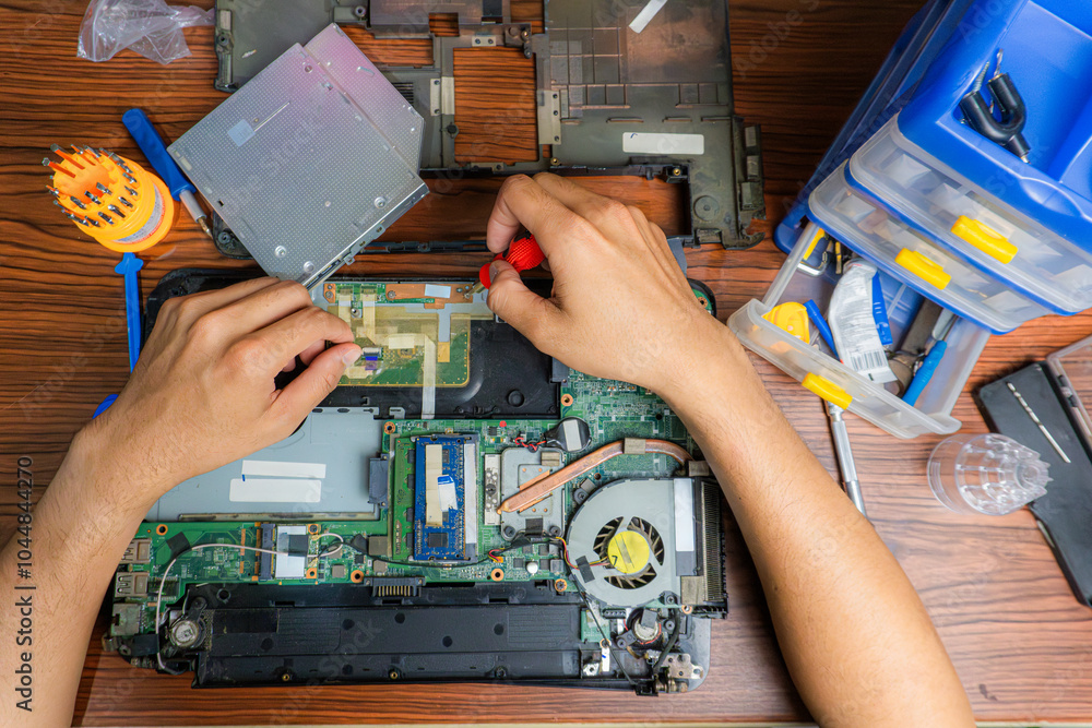 image shows a person repairing inside of a laptop. using hands to ...