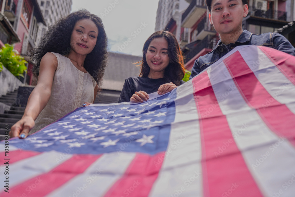 Diverse group of friends proudly holding an American flag outdoors ...