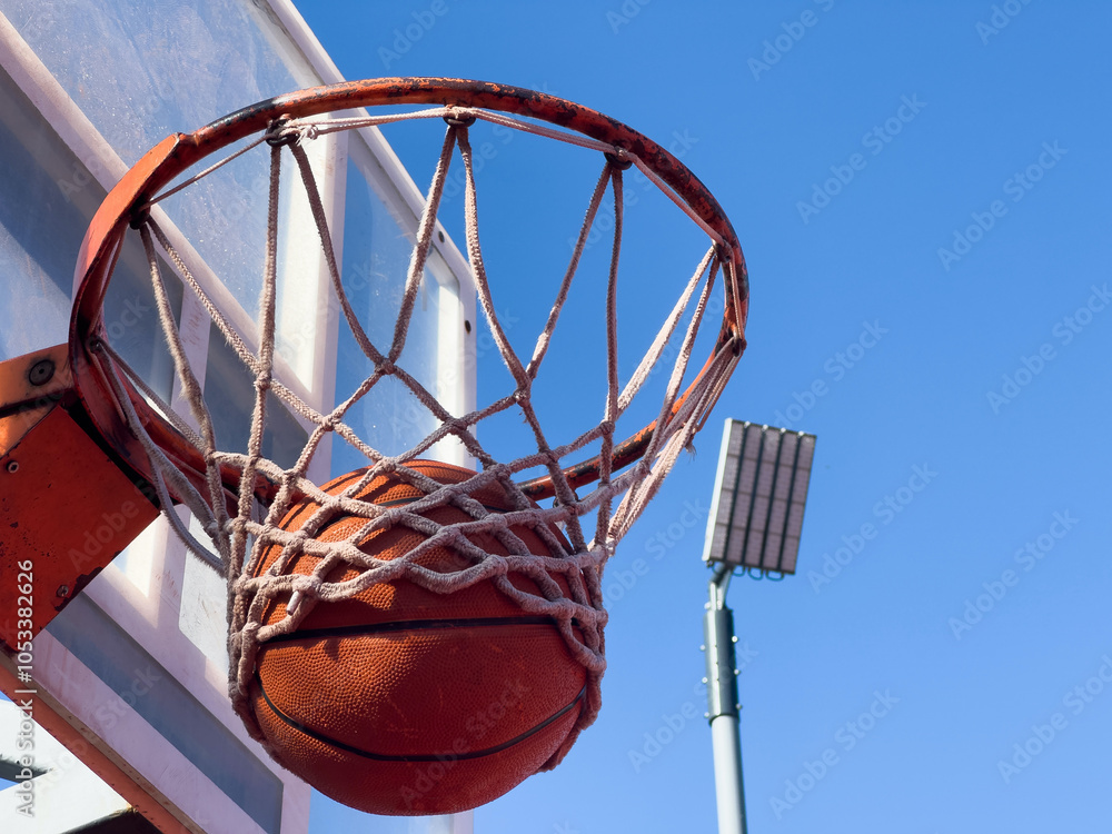 Basketball scoring a basket as it goes through the hoop and making a ...