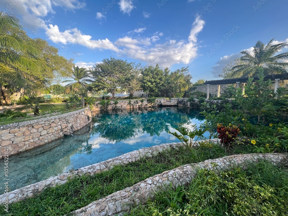 Cenote swimming pool, azure water, stone walls, blue sky with clouds ...