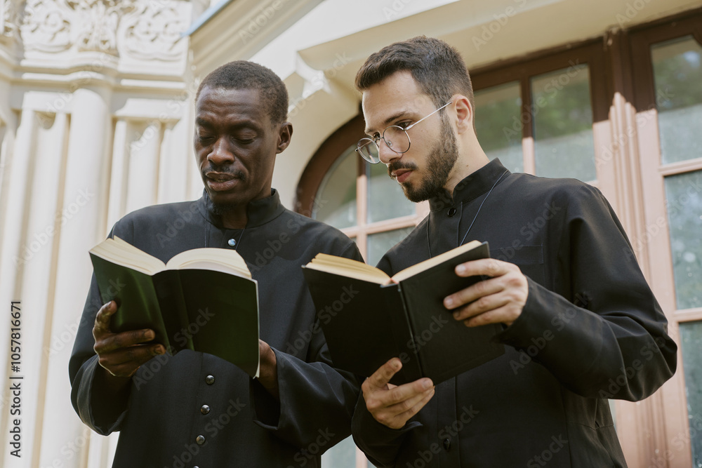 Mature African American and Caucasian priests reading holy book ...