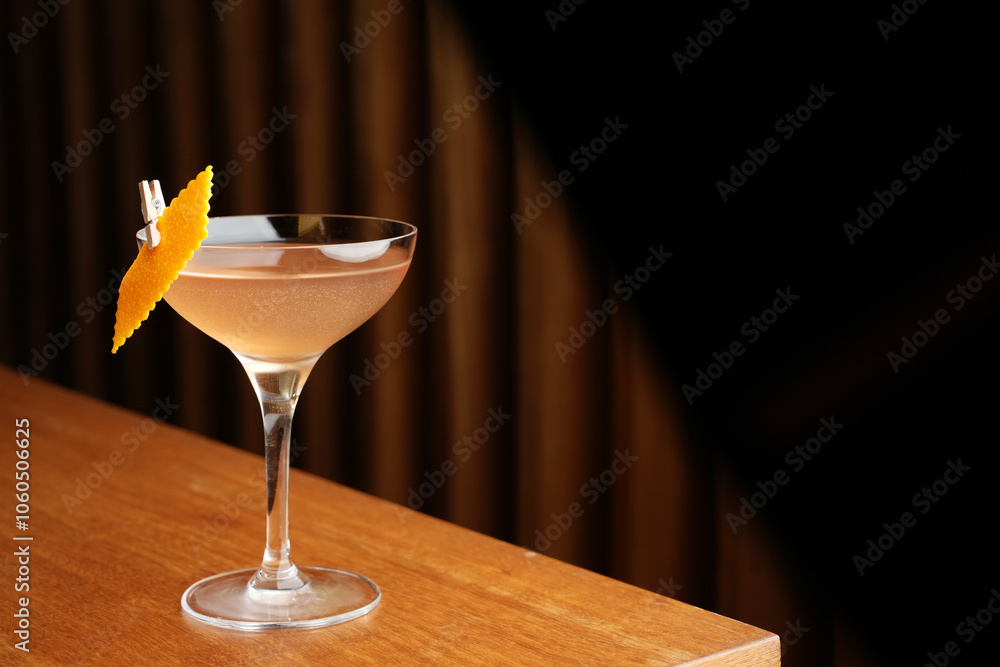 Bronx cocktail glass with orange peel slice on a wooden bar counter ...